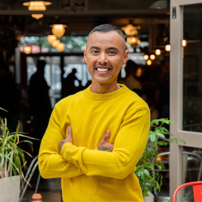 Artist Marcos Chin dressed in yellow standing outside a store